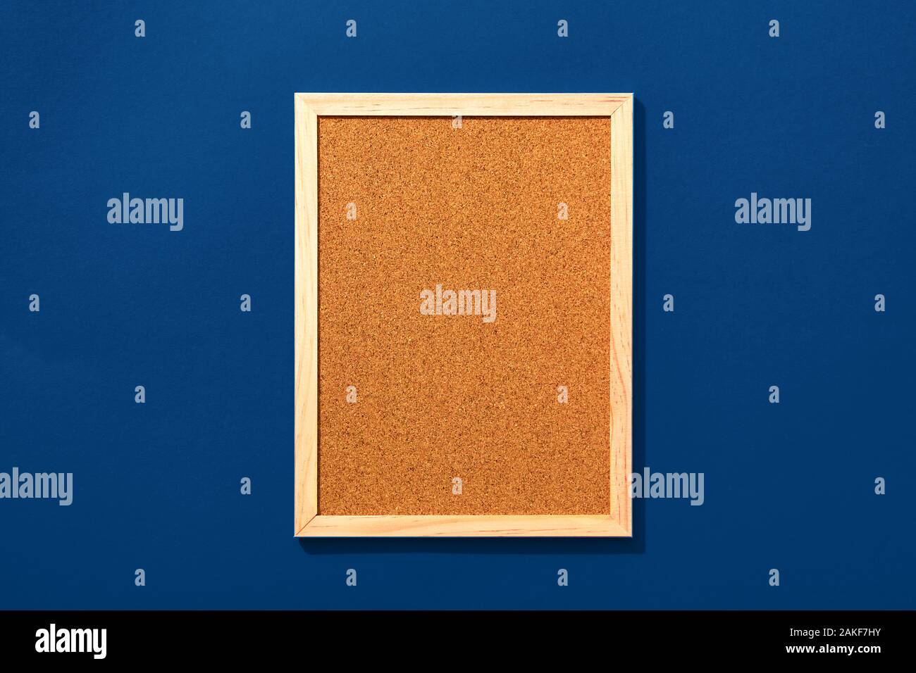 Empty cork board with wooden frame on classic blue background, view ...