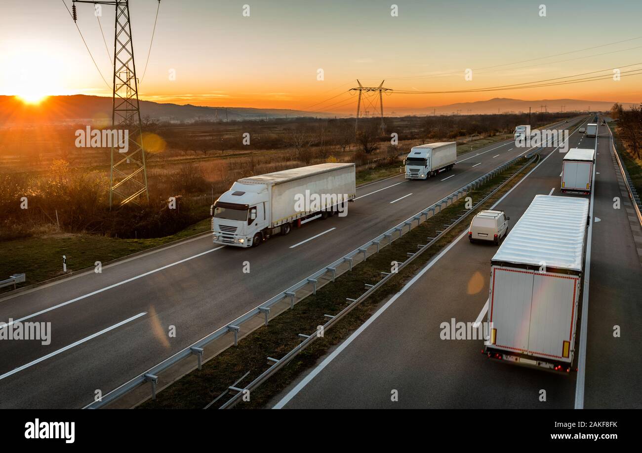 Convoys of White transportation trucks passing each other on a highway ...