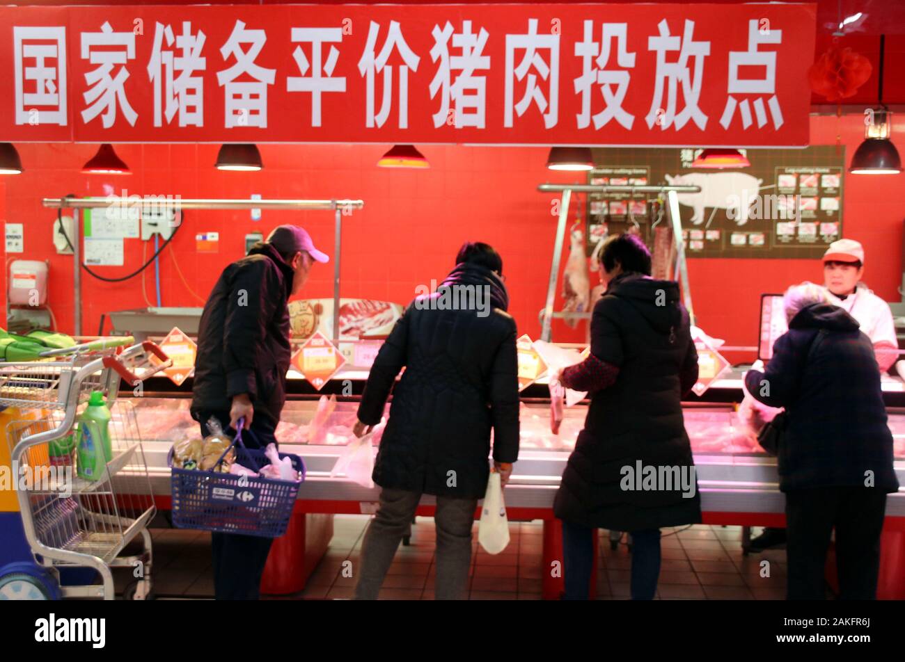 Chinese customers shop for pork and other meat products at a ...