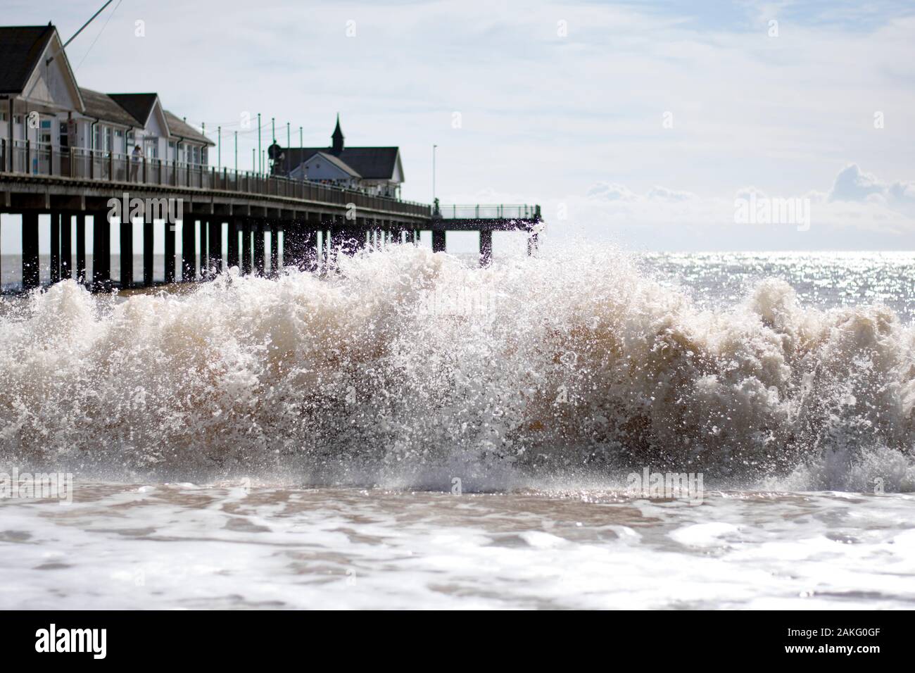 large waves crashing on beach with pier in background Stock Photo - Alamy