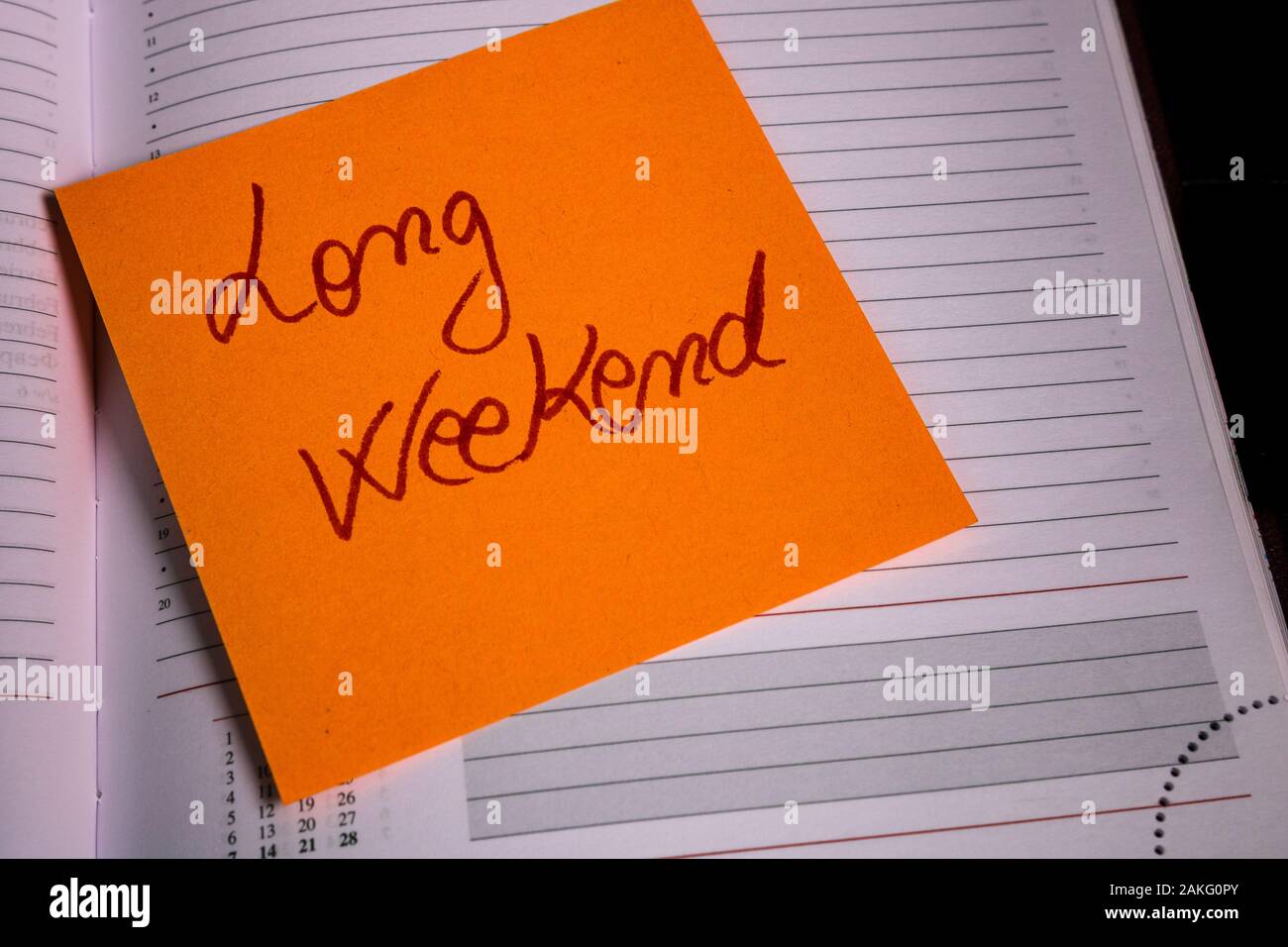 Writing long weekend on memo post reminder. Text long weekend on sticky ...