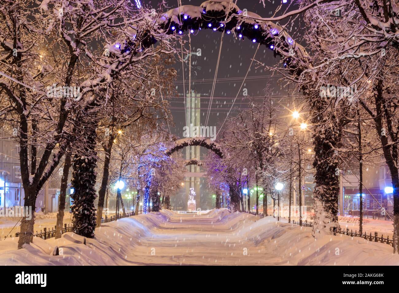 Walk of the city at night in winter. Alley with lights, trees, garlands ...