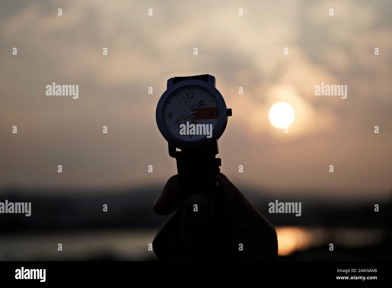 Human hand holding watch sunset background Stock Photo - Alamy