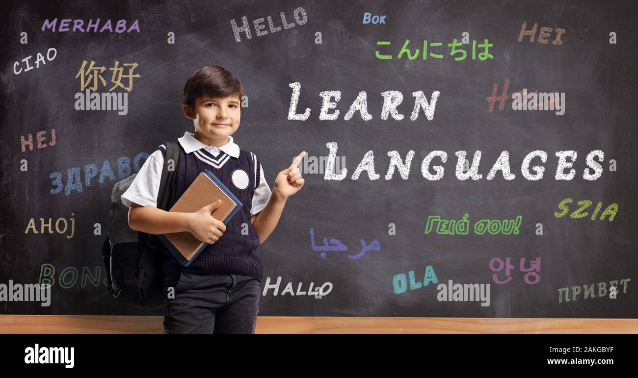 Schoolboy in a uniform pointing to a school board with text hello in ...