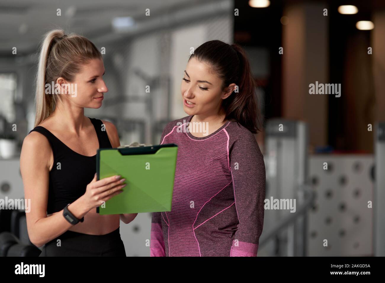 Fitness instructor and woman talking at gym Stock Photo - Alamy
