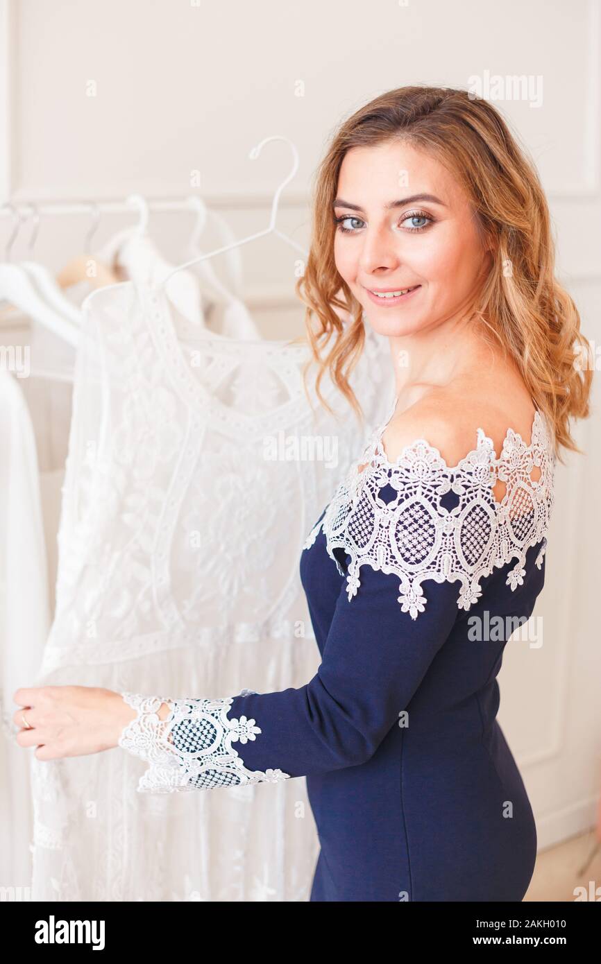 Young woman choosing transparent light lace dress among clothes on a ...