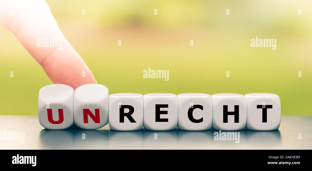 Hand turns dice and changes the German word "unrecht" ("injustice" in ...