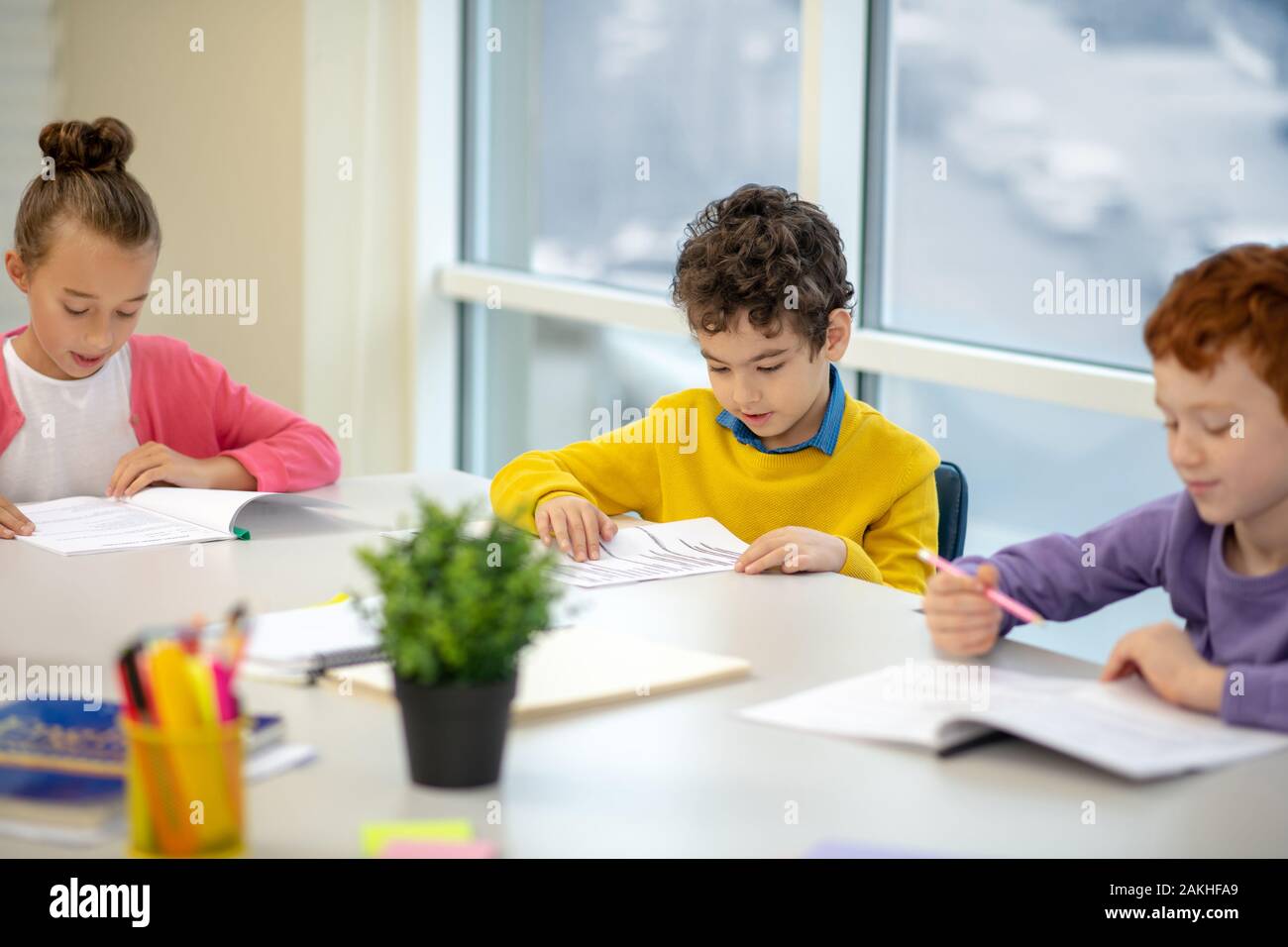Three kids studying at the class together Stock Photo - Alamy