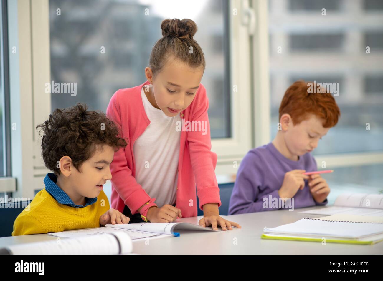 Helpful school girl explaining the task to classmates Stock Photo - Alamy