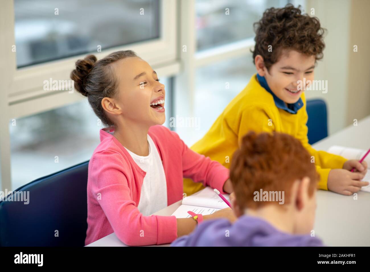 Cheerful school girl laughing during the lesson Stock Photo - Alamy