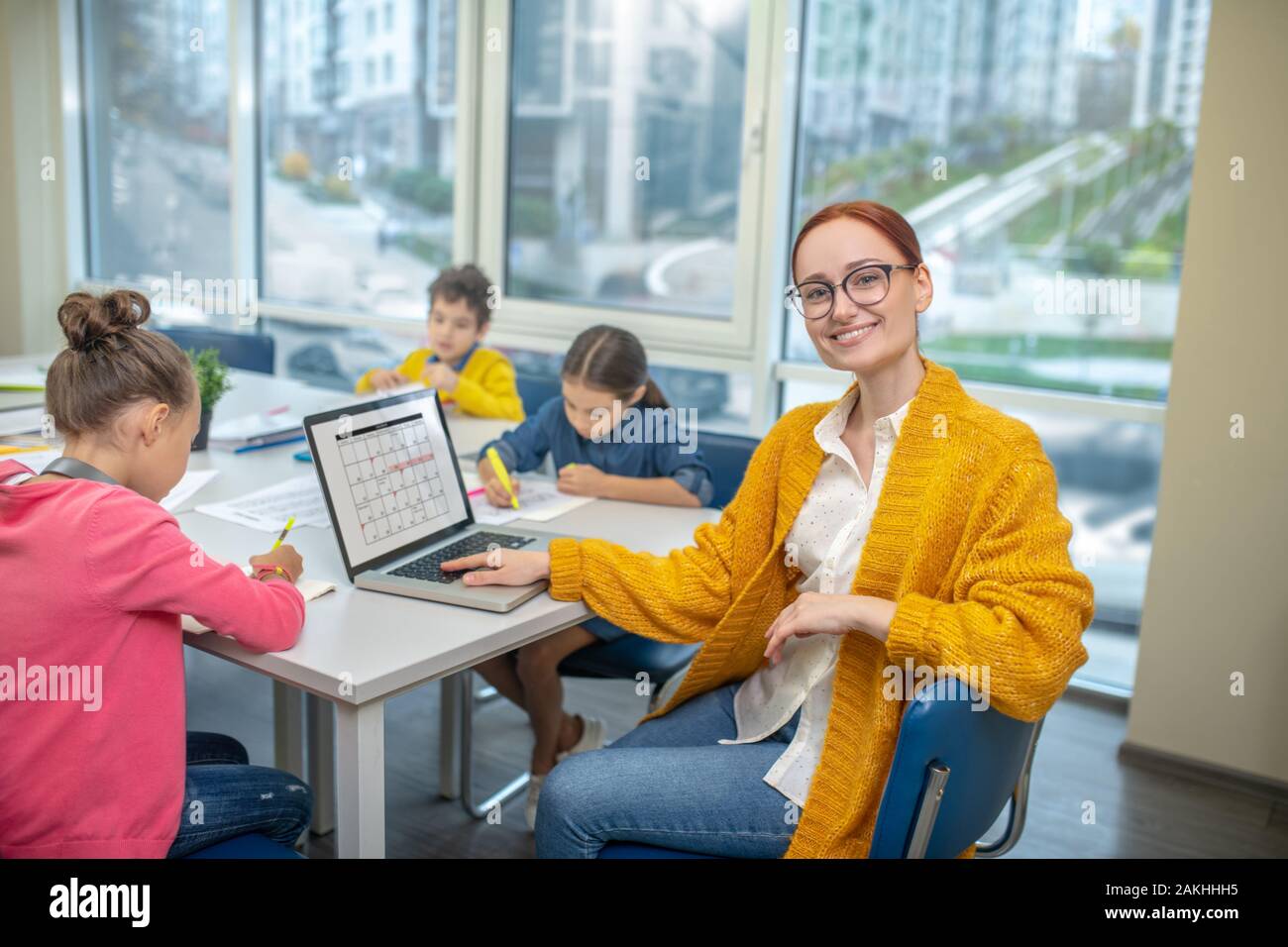 Smiling young teacher happily working with children Stock Photo - Alamy