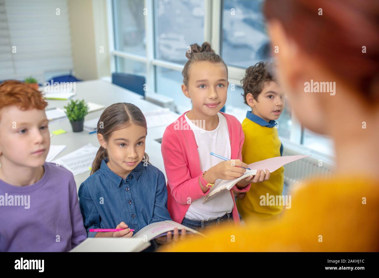 Children listening to the teacher and taking notes Stock Photo - Alamy