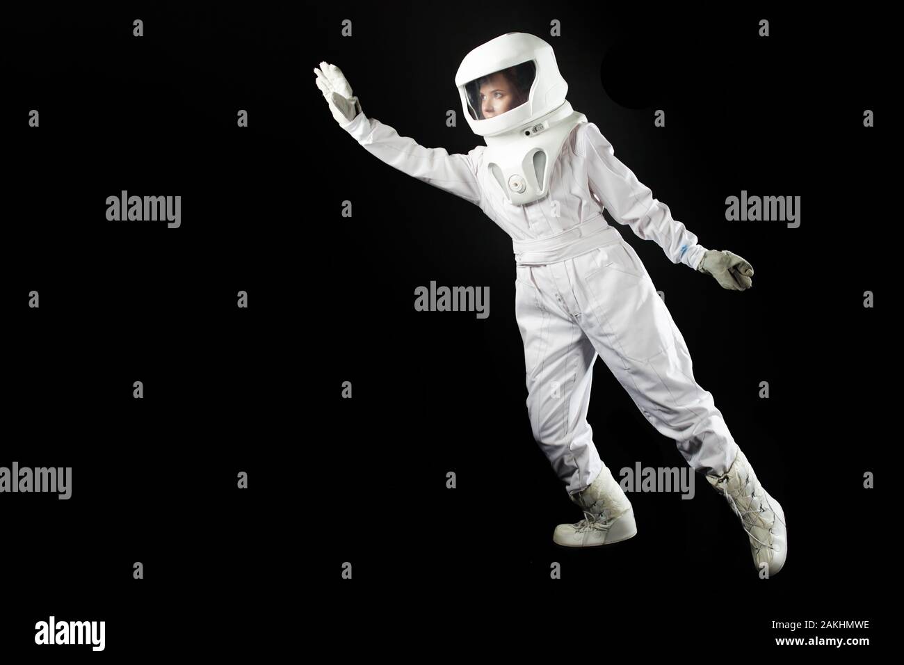 Astronaut on a black background goes forward and stretches his hand ...