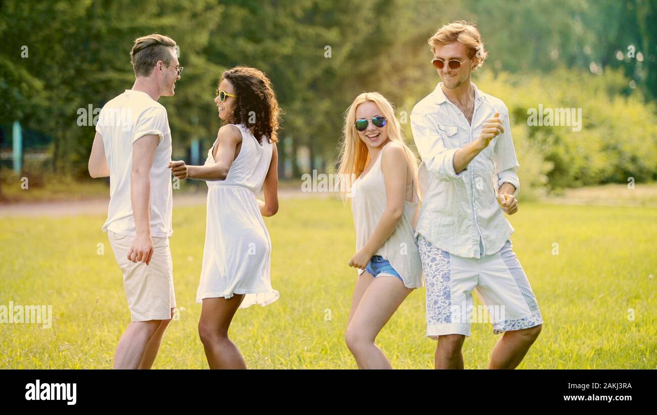 Two cute couples hanging out at open-air festival, dancing to music ...