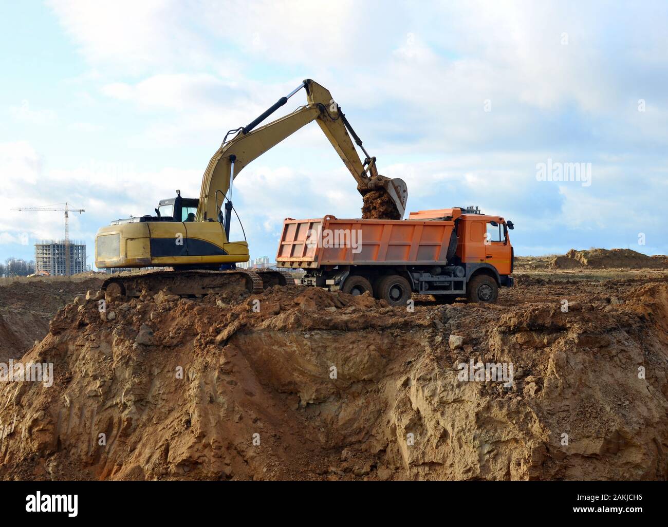 Excavator load the sand to the heavy dump truck on construction site ...