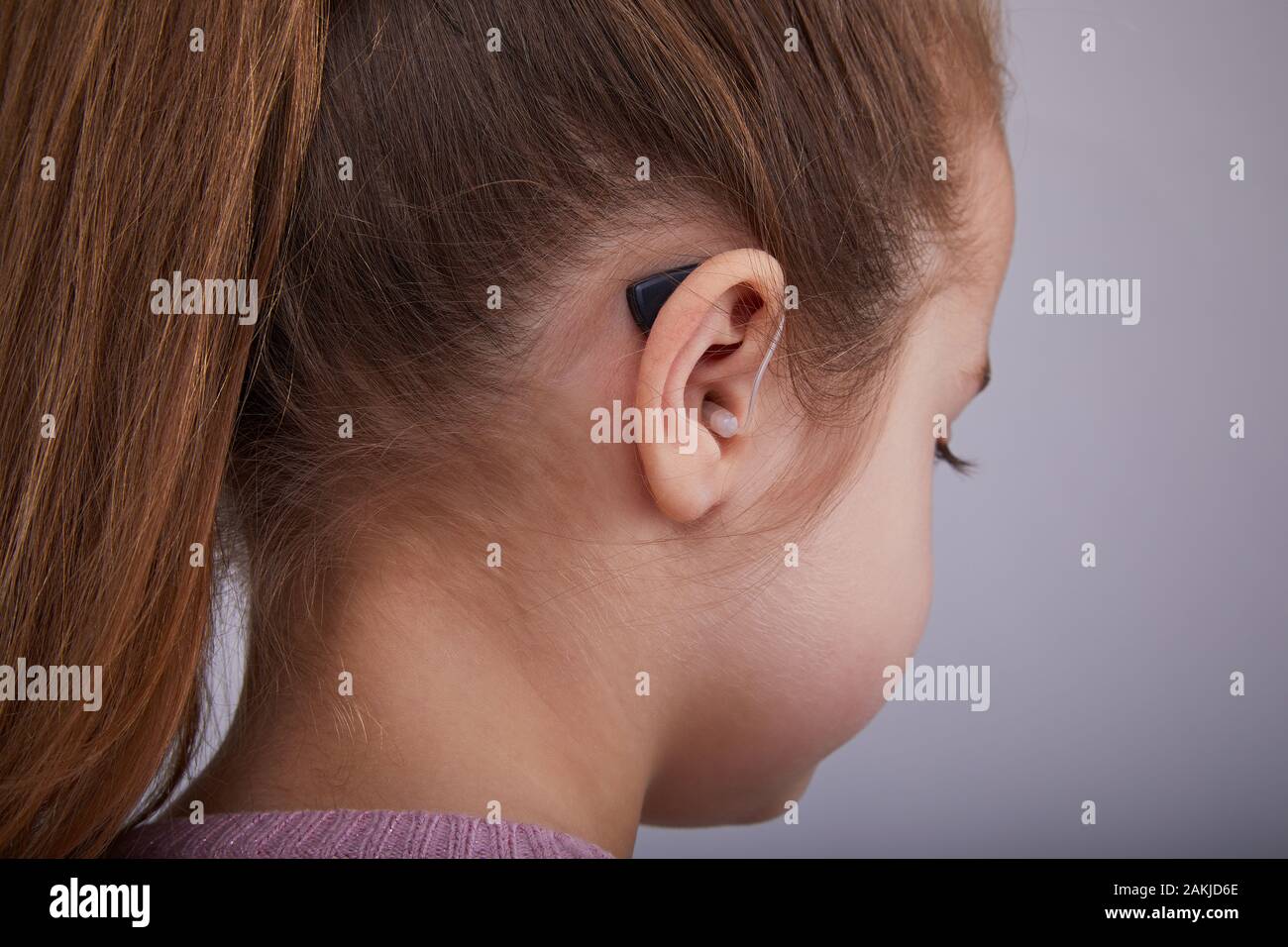 Hearing Aid in Young Girl's Ear. Toddler girl wearing a hearing aid ...