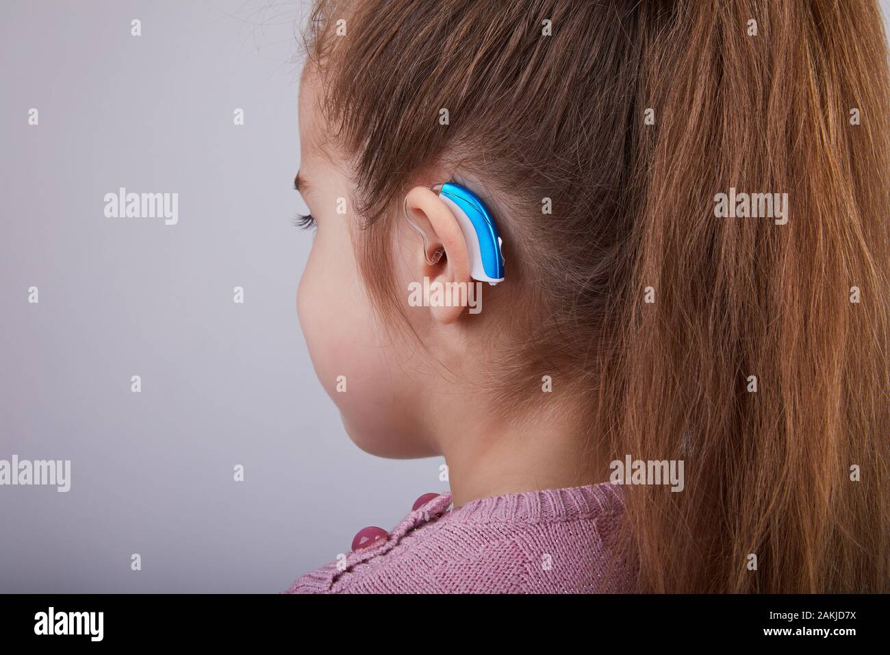 Hearing Aid in Young Girl's Ear. Toddler girl wearing a hearing aid ...