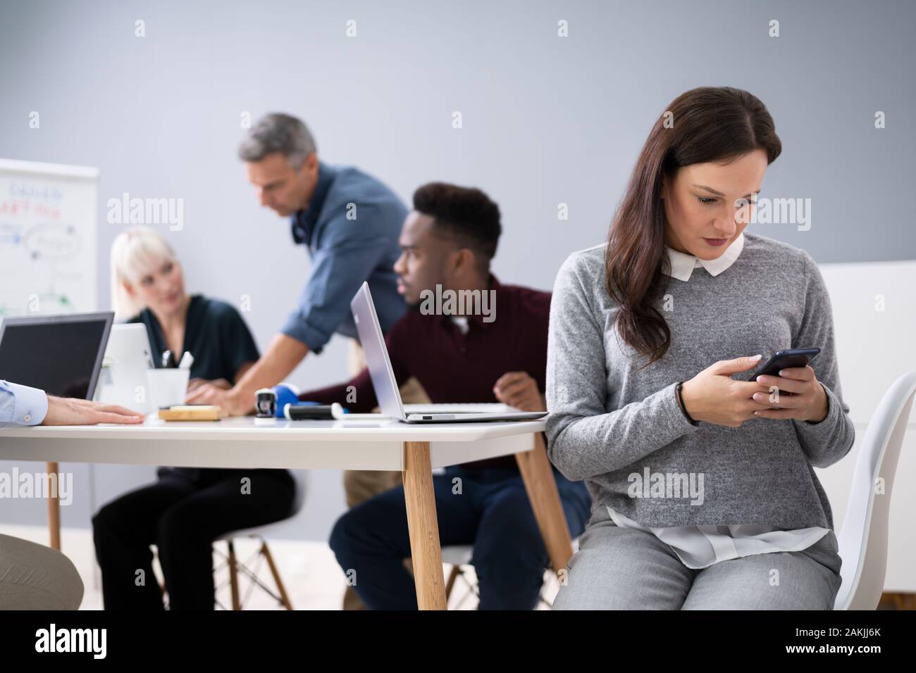 Distracted Businesswoman Using Mobile Phone In Meeting Stock Photo - Alamy