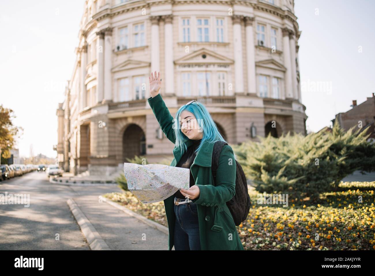 Happy female explorer holding map and waving Stock Photo - Alamy