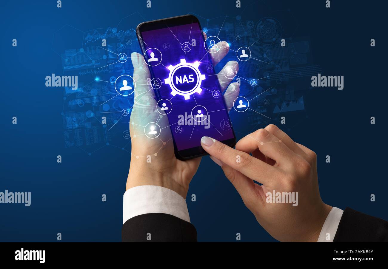 Female hand holding smartphone with NAS abbreviation, modern technology ...