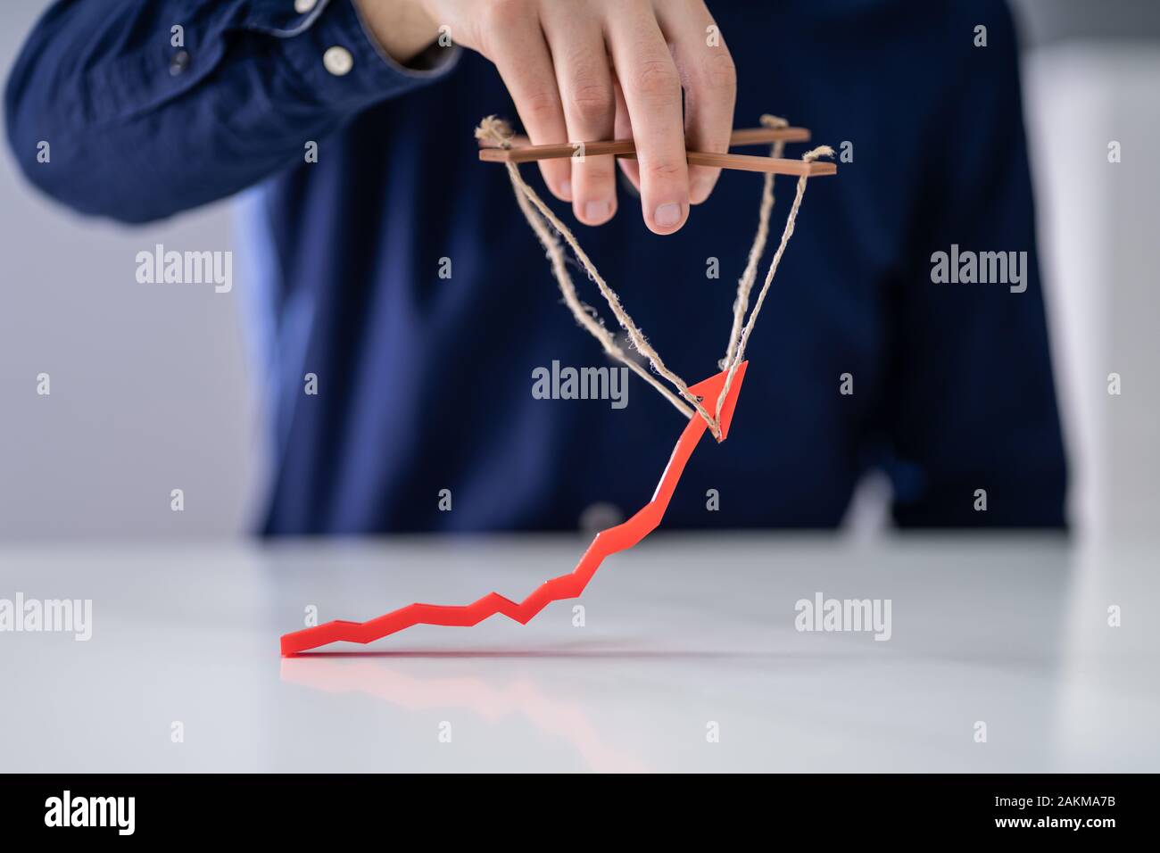 Businessperson's Hand Manipulating Red Arrow With Rope Stock Photo - Alamy