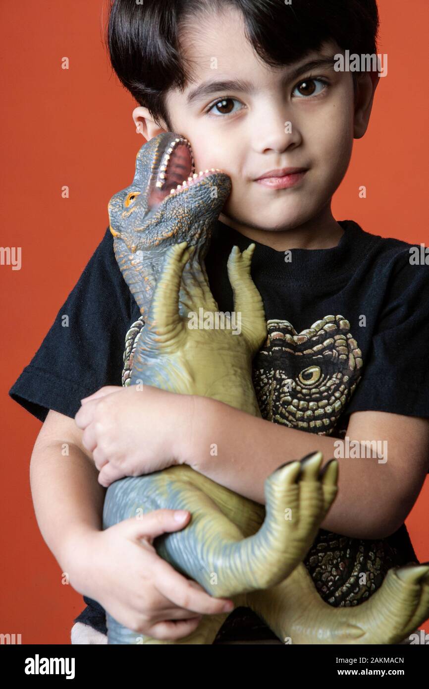 Portrait of a Young Caucasian boy posing with his favorite dinosaur toy ...