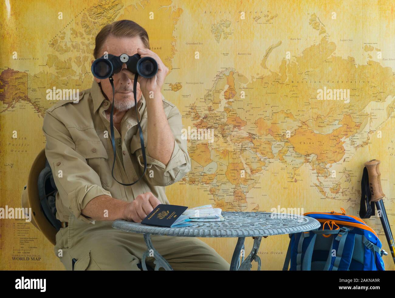 senior man sitting at cafe table with map background and hiking pack ...