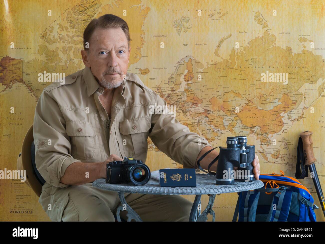 senior man sitting at cafe table with map background and hiking pack ...