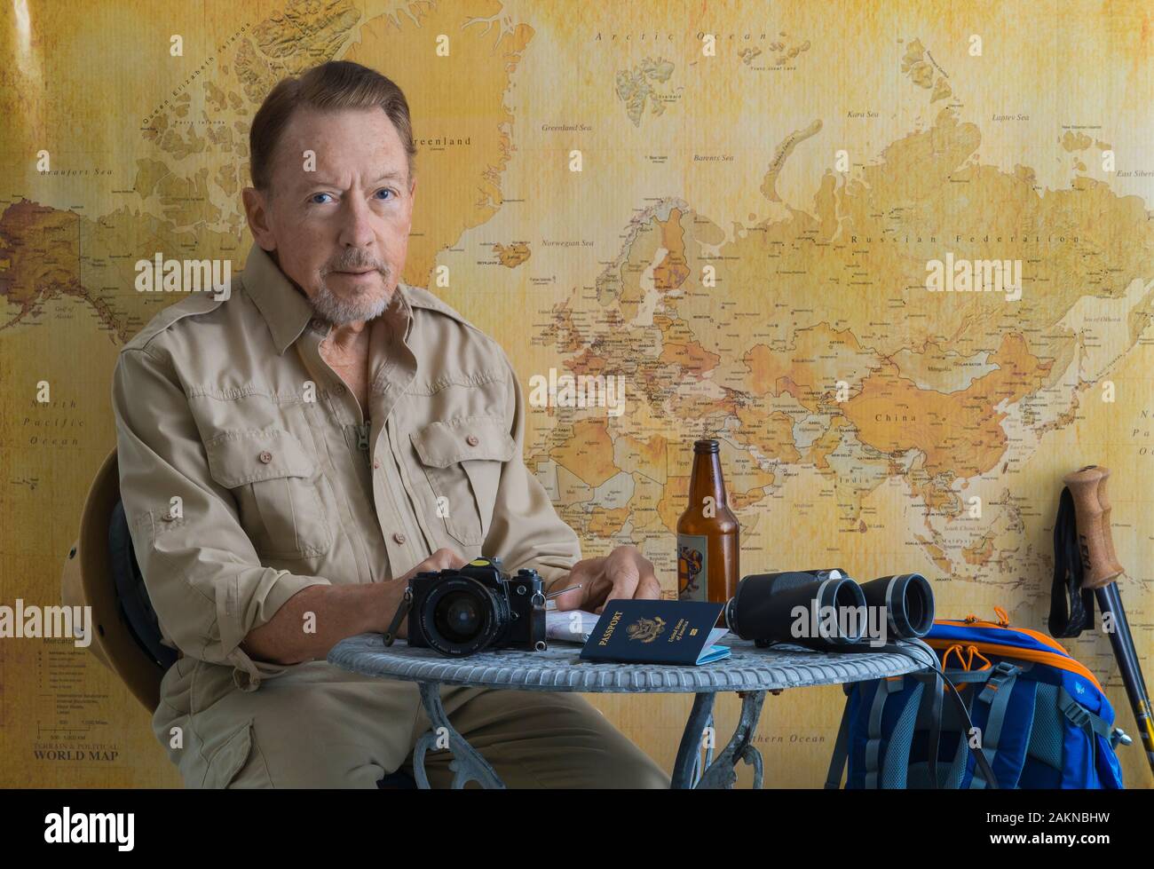 senior man sitting at cafe table with map background and hiking pack ...