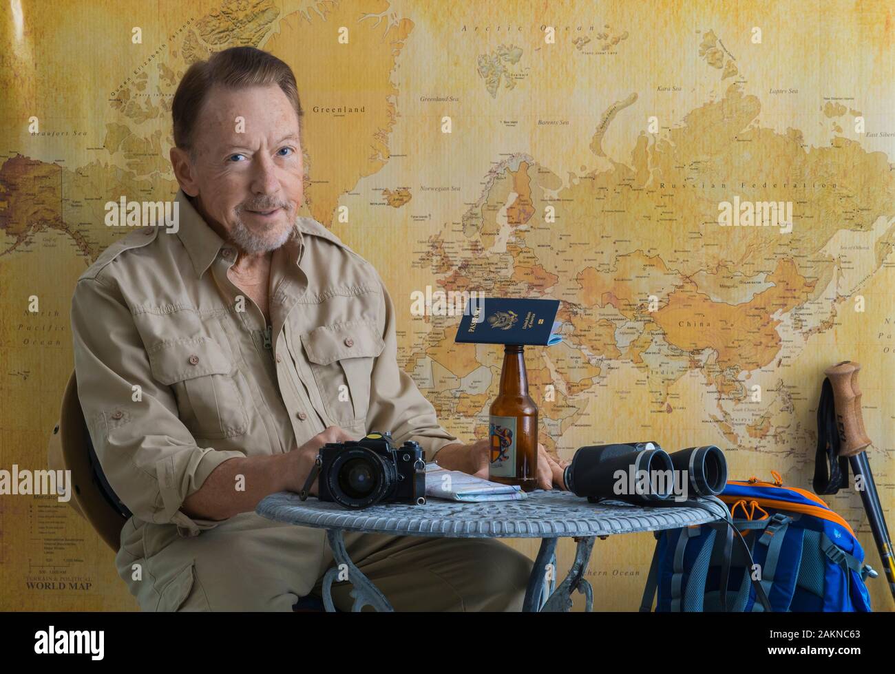 senior man sitting at cafe table with map background and hiking pack ...