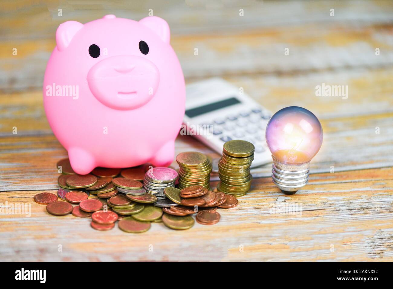 light bulb with light from the lamp and coin piggy bank on wooden table ...