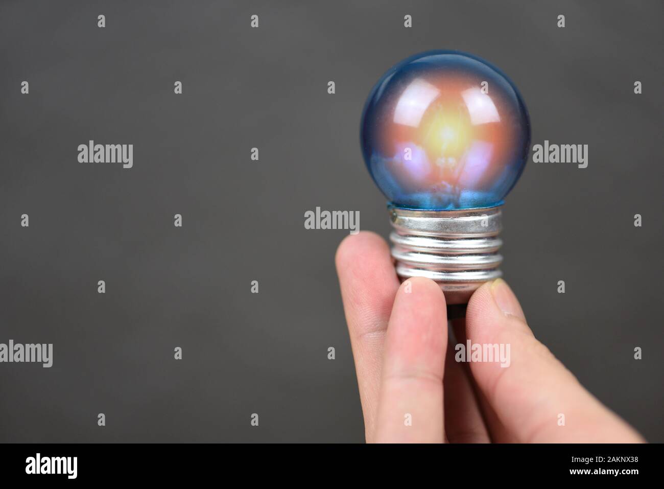 Hand holding light bulb with light from the lamp on black background ...