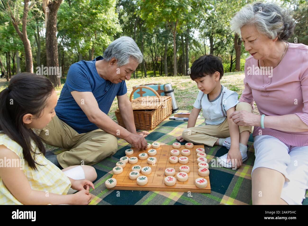 Happy family outdoors playing chess Stock Photo - Alamy