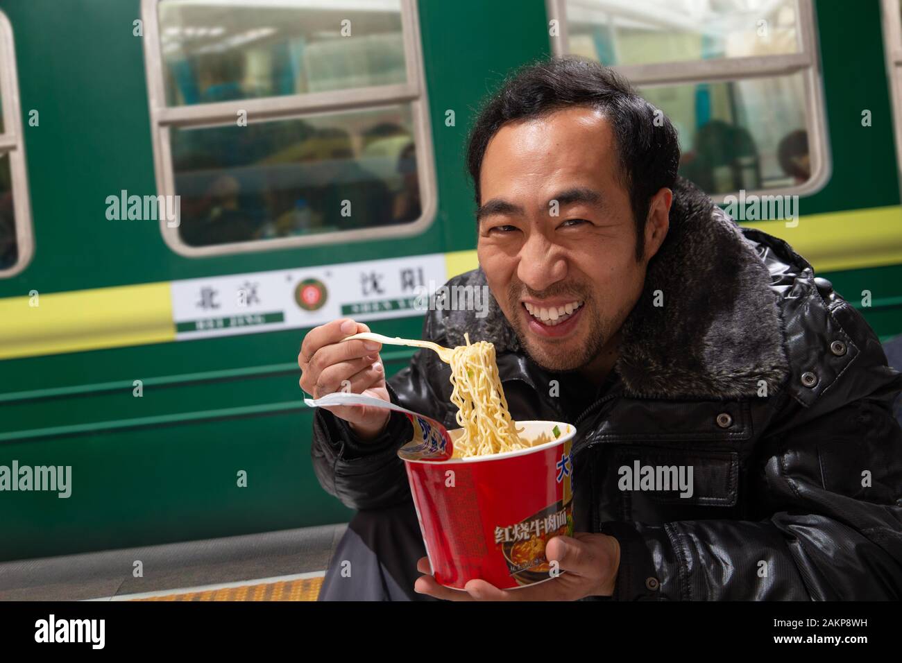 Passengers eating instant noodles on the podium at the railway station ...