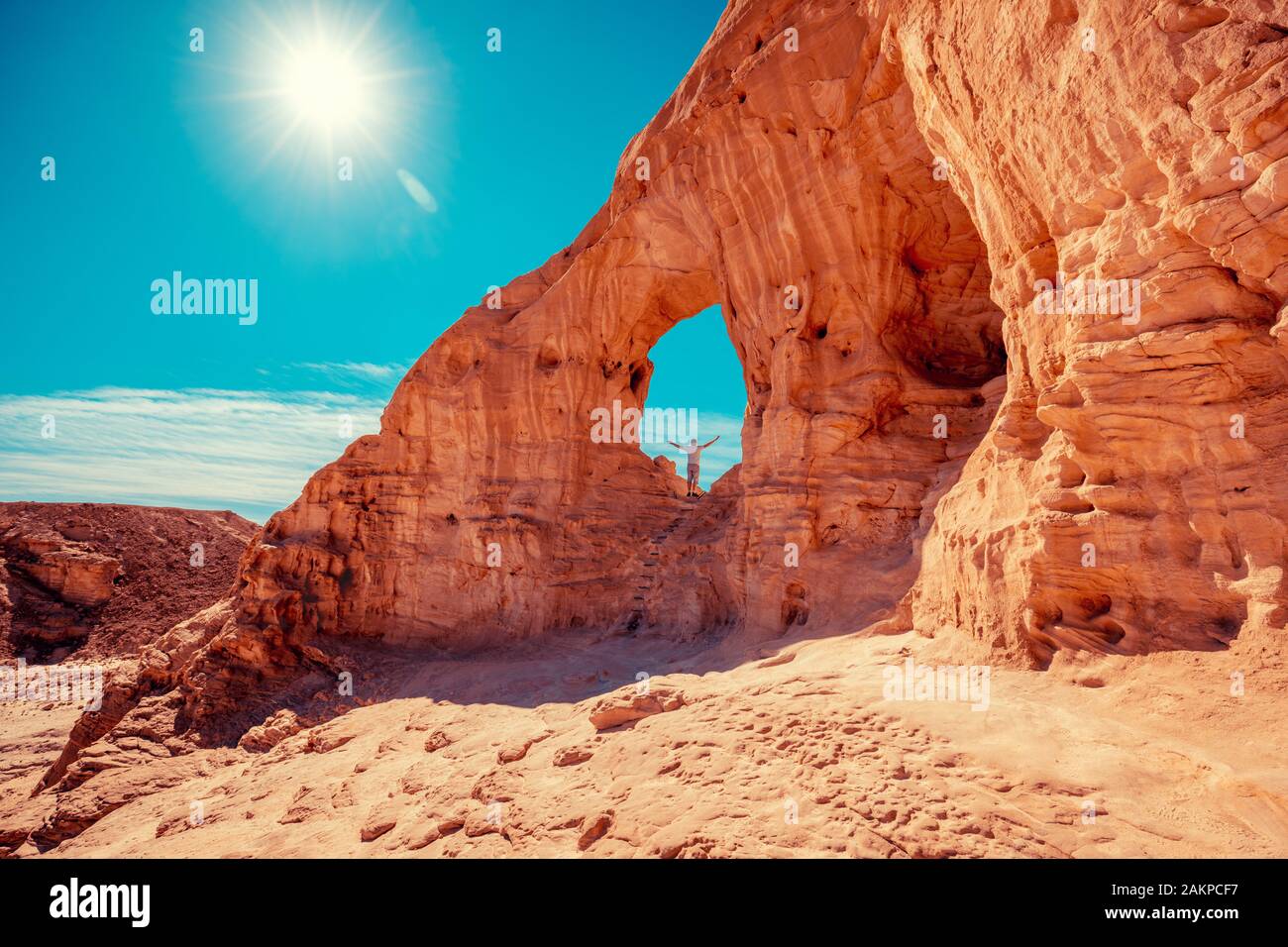 Arch in the rock. A human with hands in the air stays in the arch ...