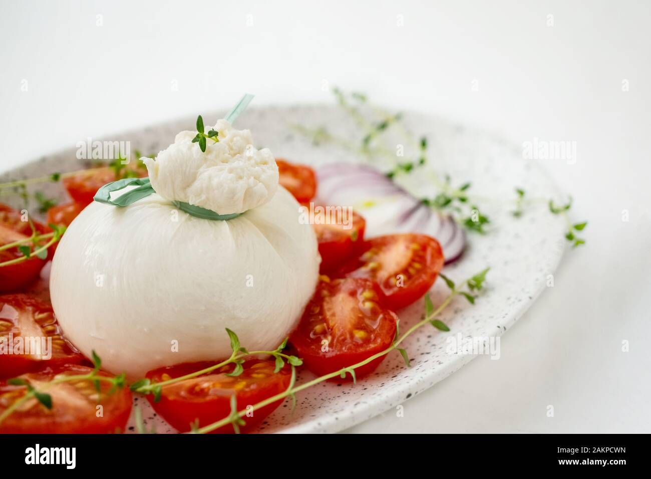 Fresh Italian burrata cheese with tomato slices on a light plate on a ...