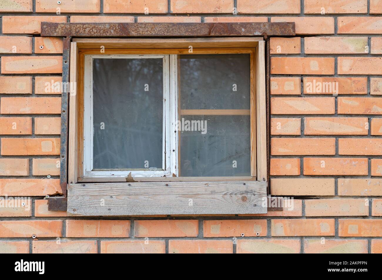 A small window in a brick wall. Ugly window in the wall of red brick ...