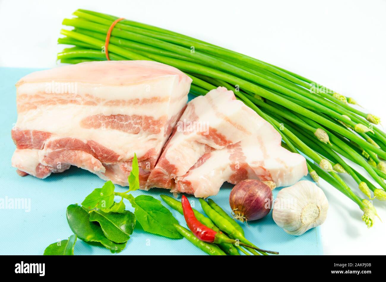 streaky pork on blue block with vegetable on white background Stock ...