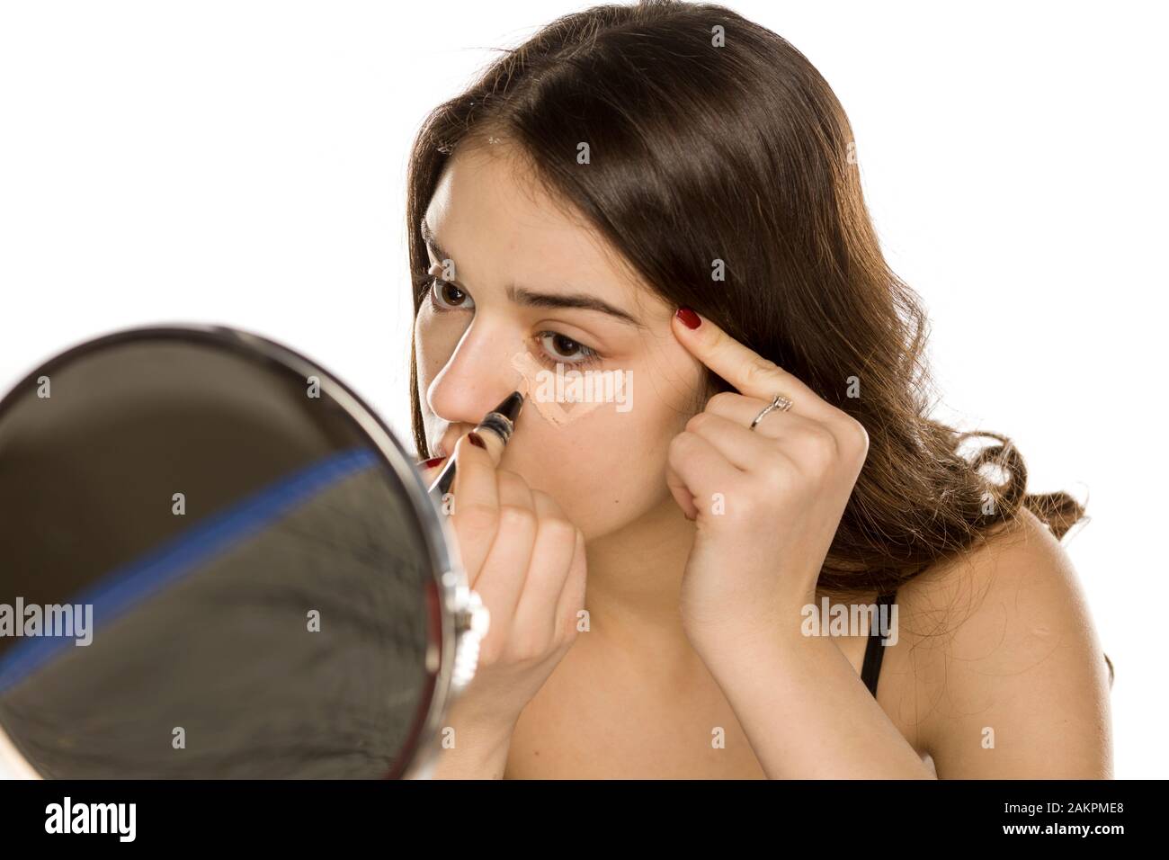 Young beautiful woman applying concealer on white background Stock ...