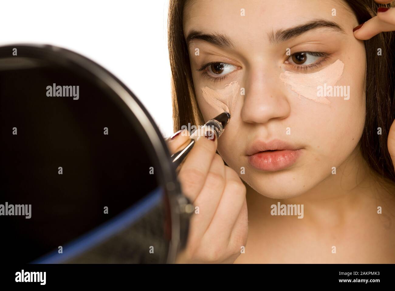 Young beautiful woman applying concealer on white background Stock ...