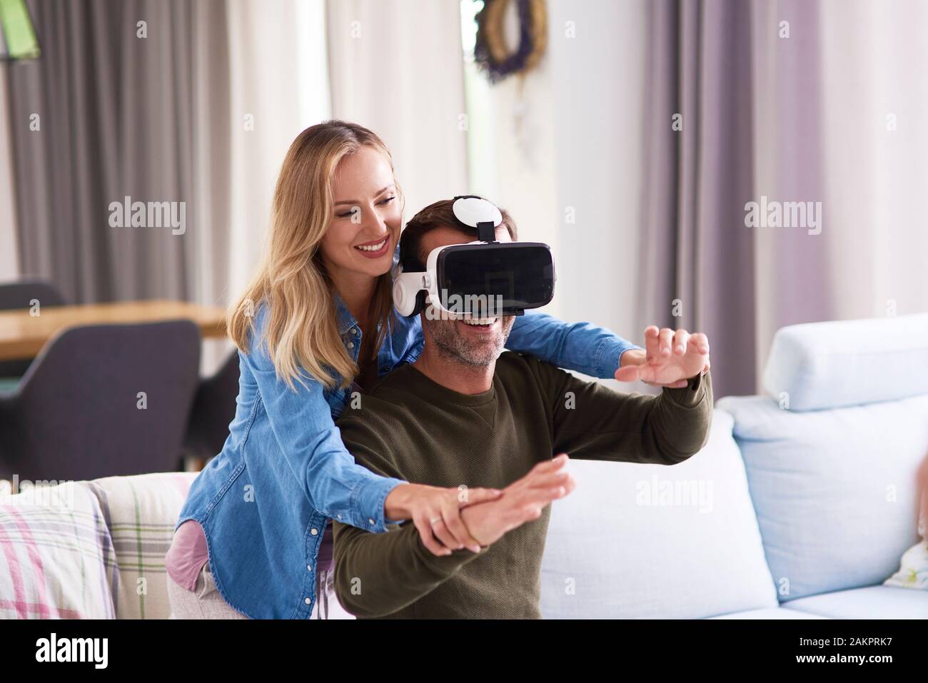 Modern couple using virtual reality simulator in living room Stock ...
