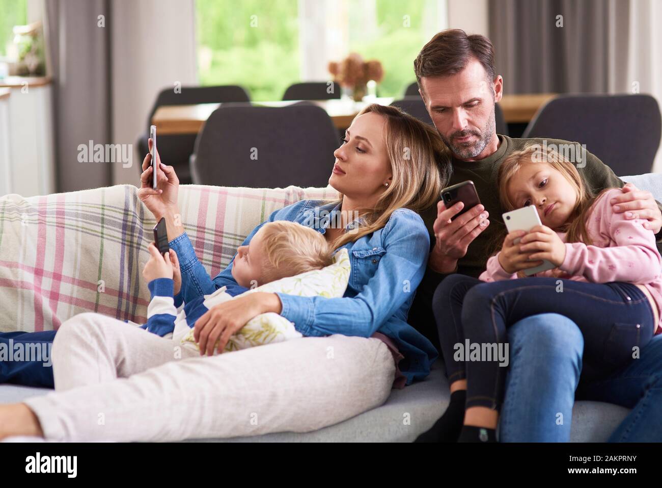 Parents and children using mobile phone in living room Stock Photo - Alamy