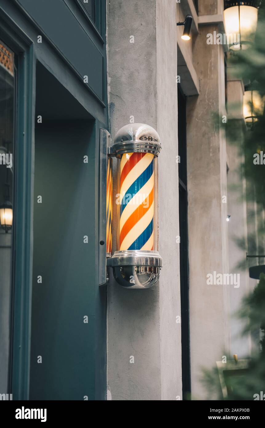 barber pole on grey wall with green wooden barber shop Stock Photo - Alamy