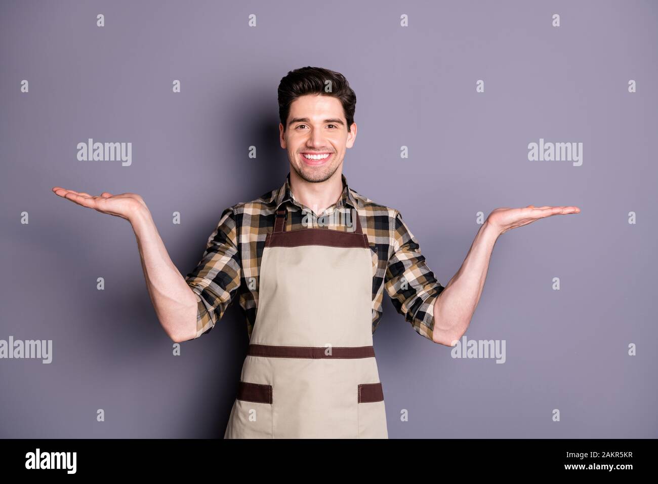 Photo of cheerful handsome man holding two sides of one object with ...