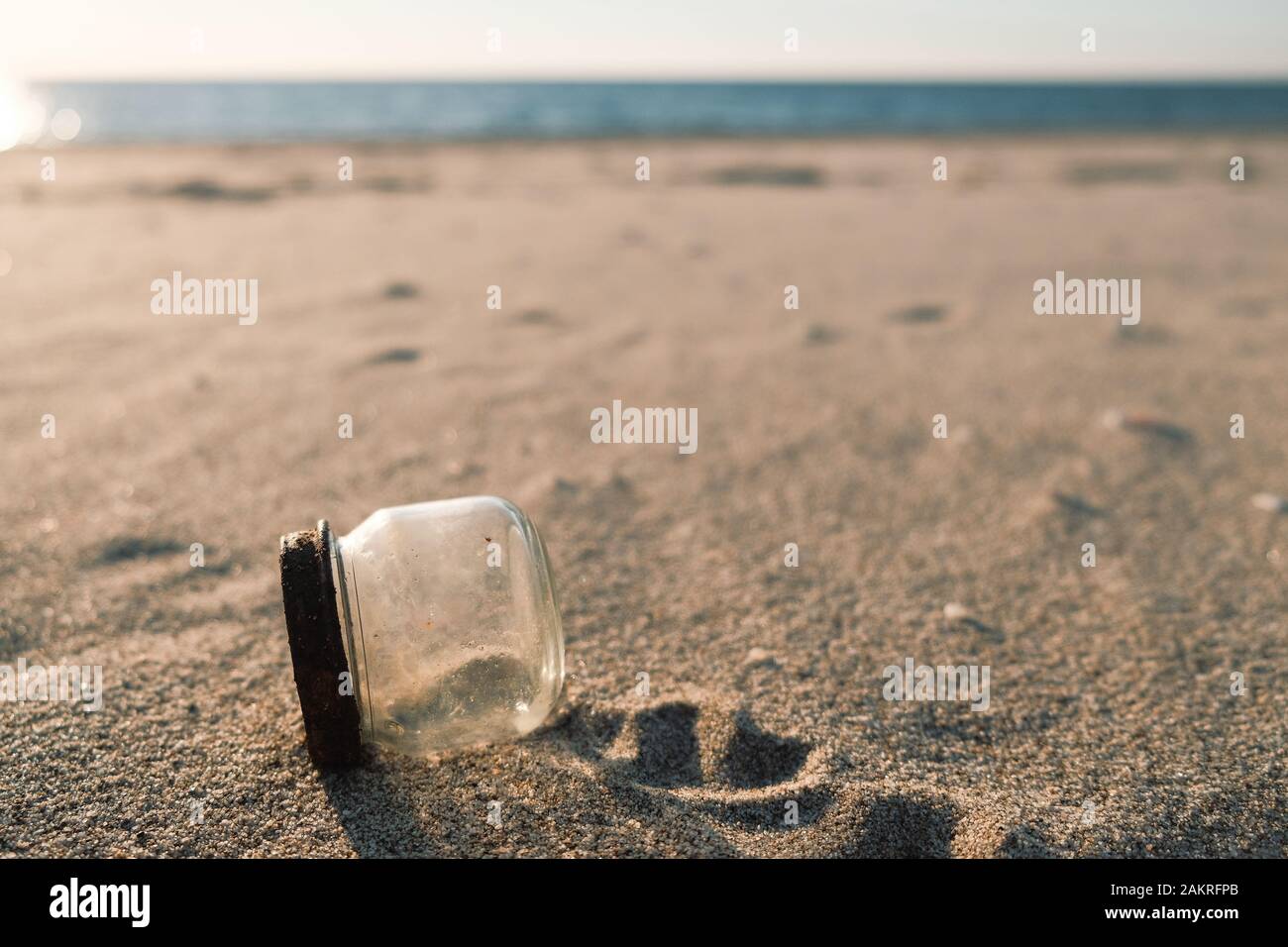 Glass container jar trash on sandy sea coast, polluted ecosystem ...