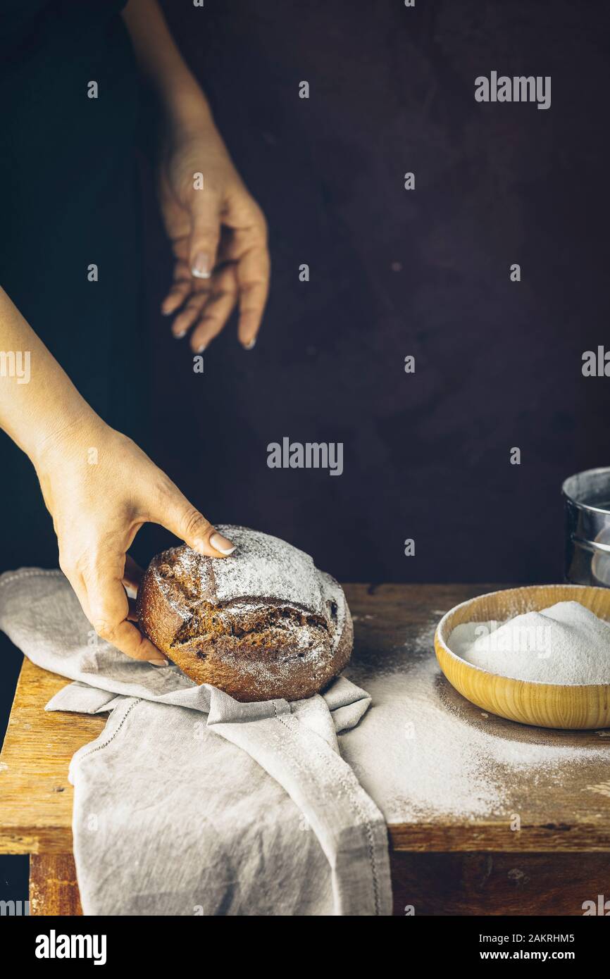 Baker's hands with a bread. Photo with high contrast. Woman hand with ...