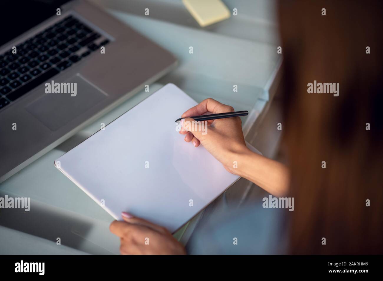 Nice young woman holding a pencil while drawing Stock Photo - Alamy