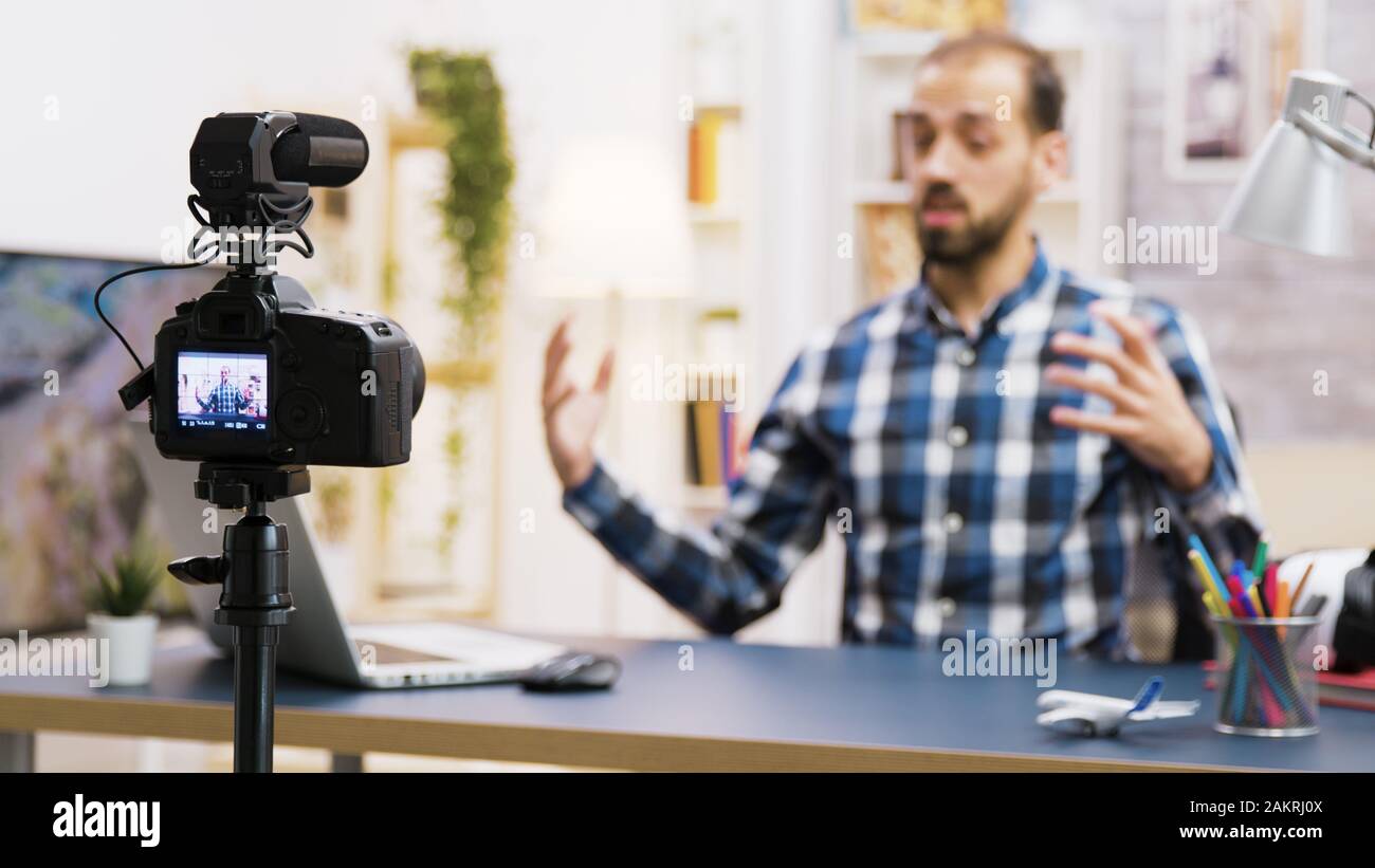 Vlogger sitting at desk in living room talking and looking at the ...