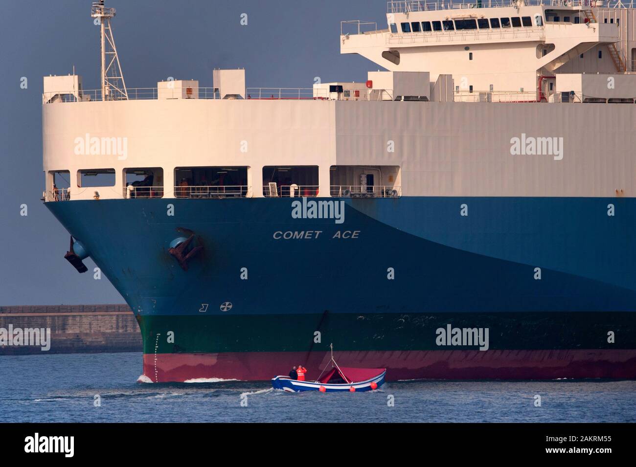 Old fashioned coble fishing boat sailing past huge cargo ship on the ...