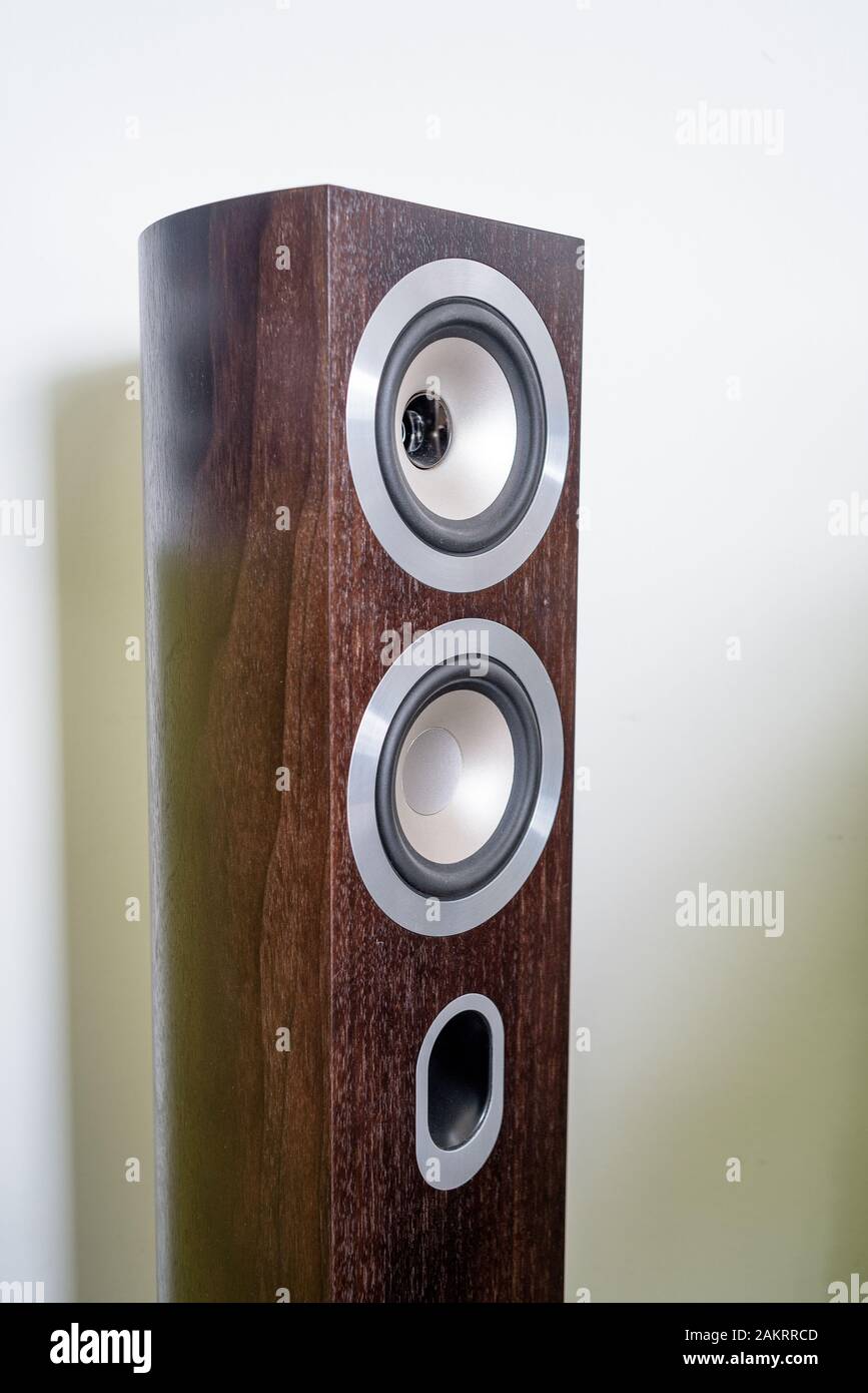Hi-Fi floorstanding cherry wood speaker against a white wall background ...